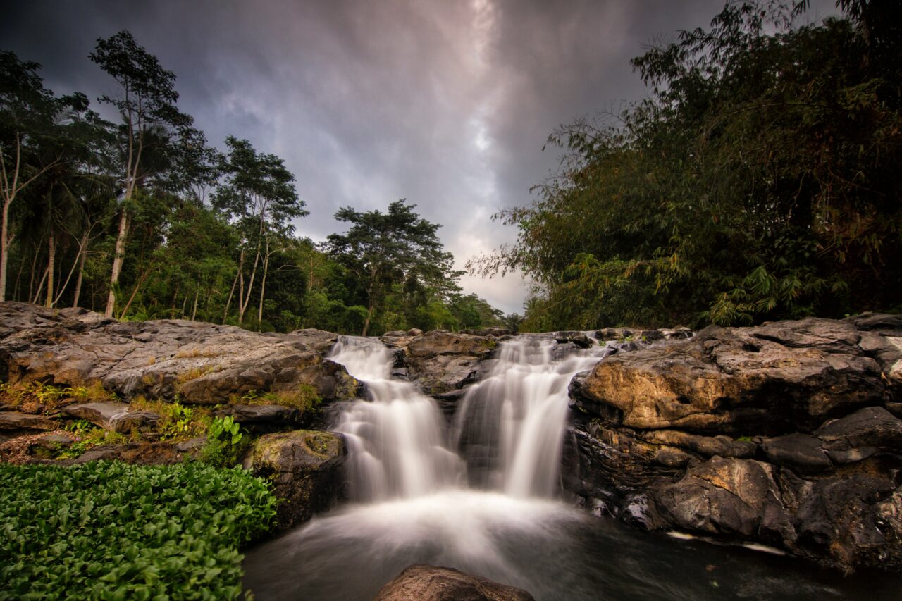 Serene Waterfall Over Stones with Lush Greenery Wallpaper | Background ...
