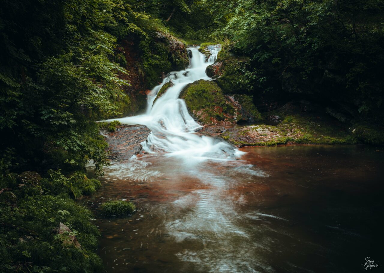 Tranquil Waterfall Over Stones in Lush Greenery Wallpaper | Background ...