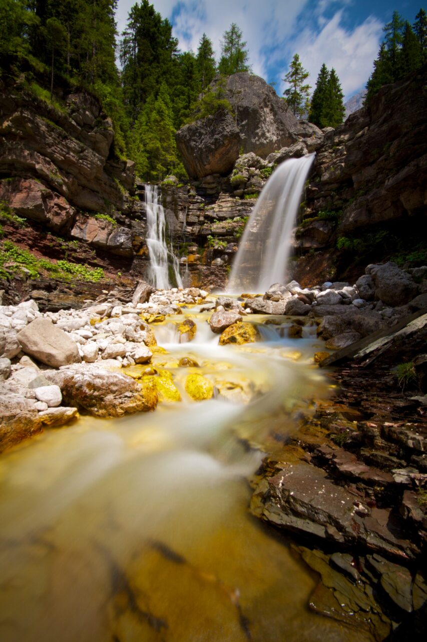 Vibrant Waterfall Over Rocks with Pine Trees Wallpaper | Background ...